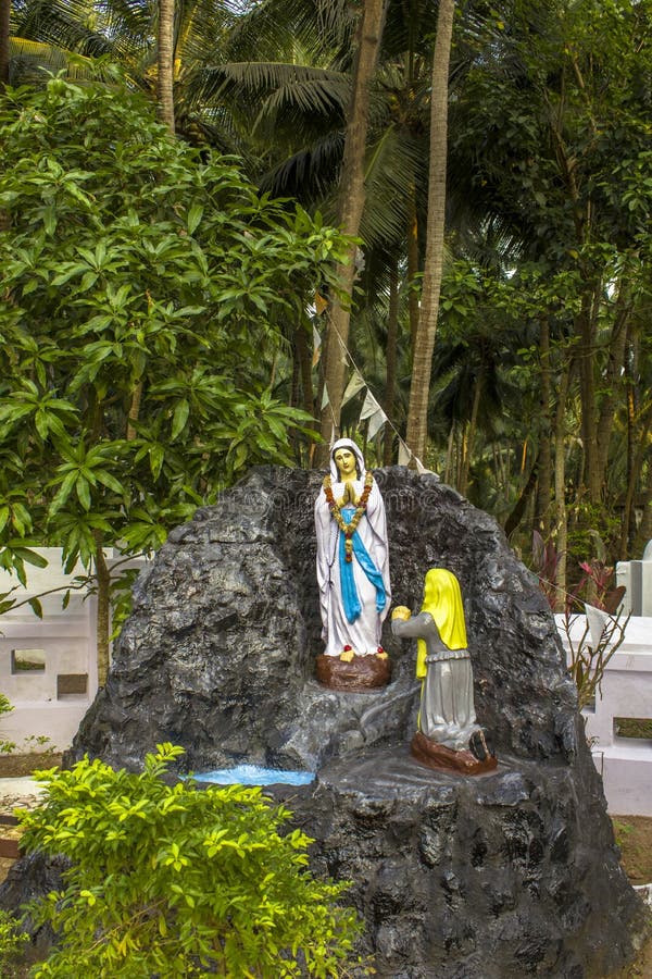 Statue of the Virgin Mary on a Stone on a Background of Green Palm ...