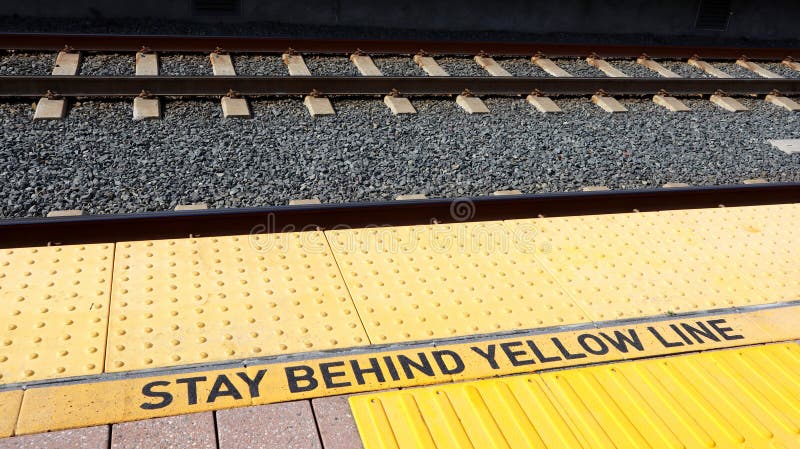 Stay Behind Yellow Line Warning Sign on Platform at Train Station Stock ...