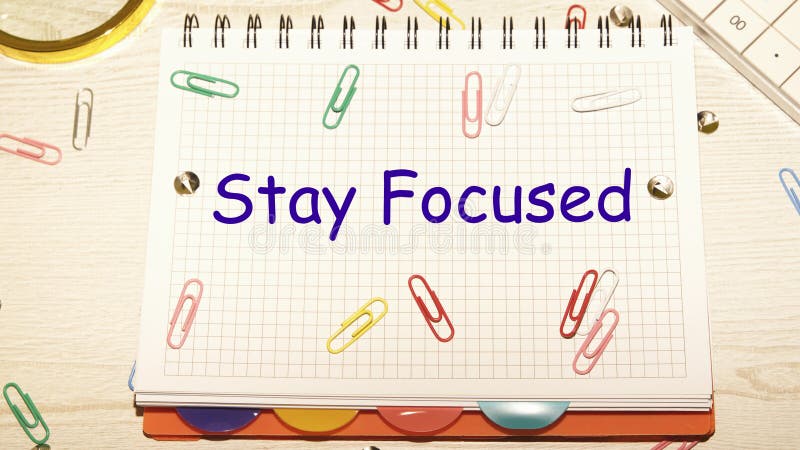 STAY FOCUSED Text on a Notebook in a Cage with Scattered Paper Clips on ...
