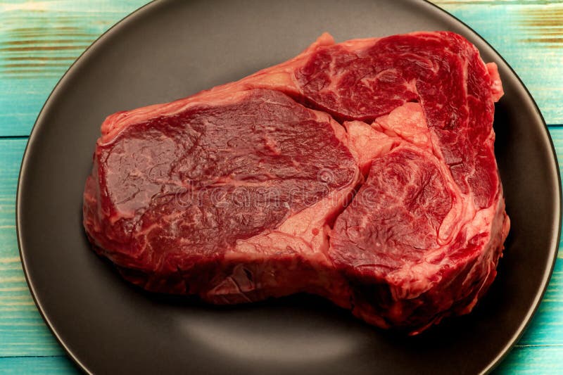 Steak Cooking Process. the Meat is in a Black Plate. a Piece of Raw ...