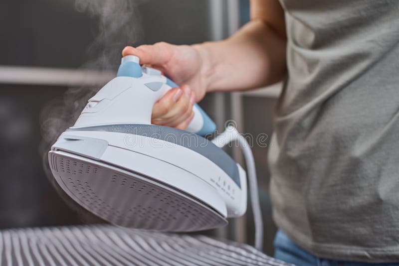 Steam Boost on the Modern Iron. Woman Ironing Clothes with Modern Iron ...