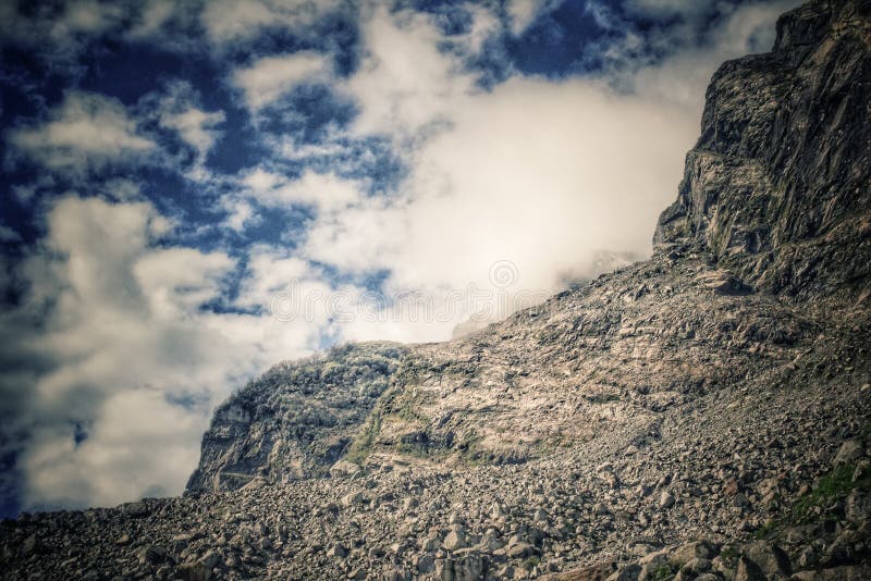 Steep Cliff Drop from a Mountain with Deep Blue Sky and Clouds Stock ...