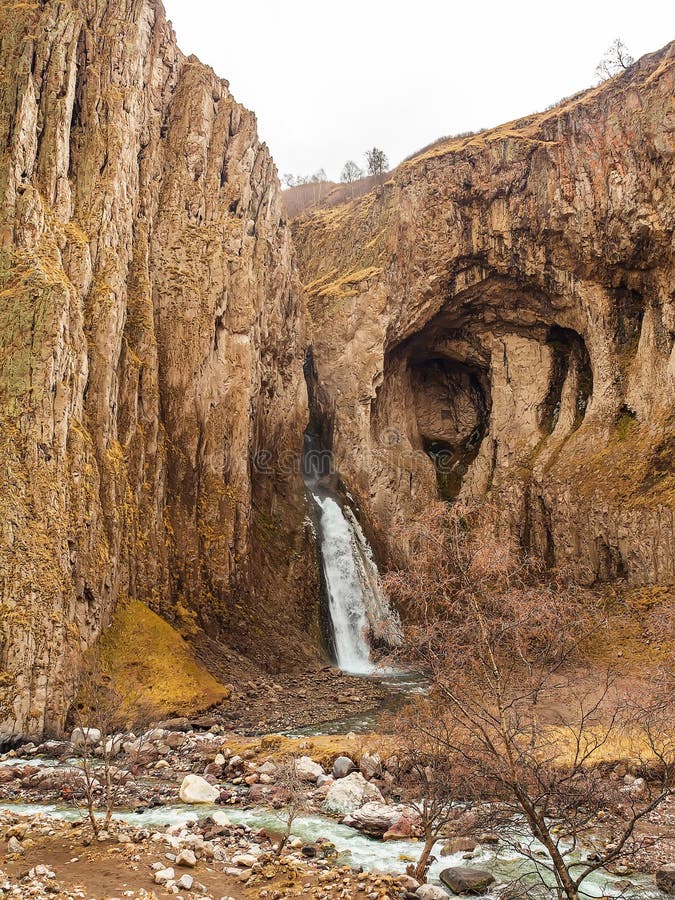 In the Steep Cliffs with Caves, a Powerful Stream of a Waterfall Flows ...