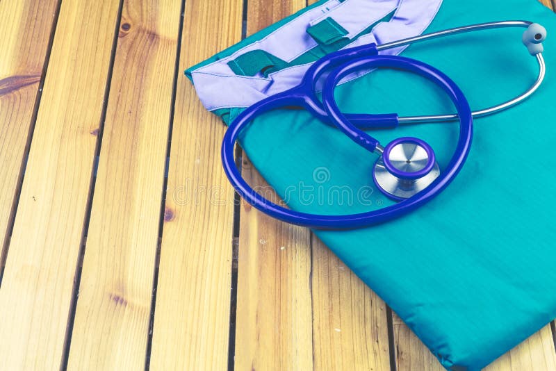 A Stethoscope and Blue Medical Uniform Stack on Wooden Stock Photo ...