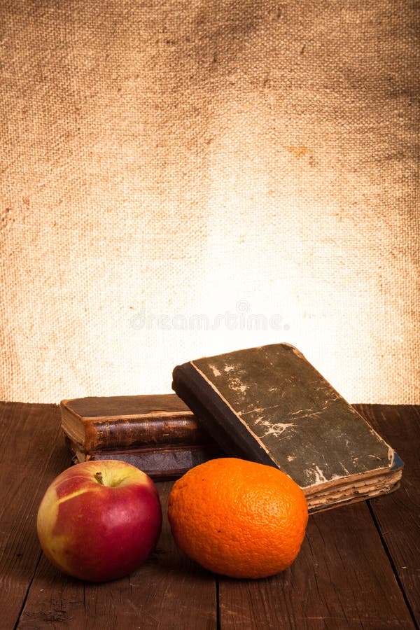 Still Life with Apple, Orange and a Stack of Old Books on Old Wooden ...