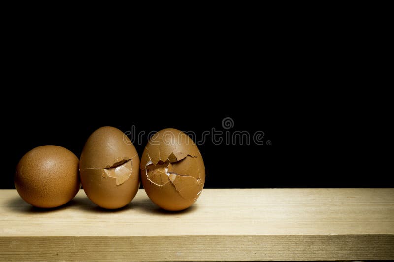 Next Egg To Break - Three Eggs on Table Against Black Background Stock ...