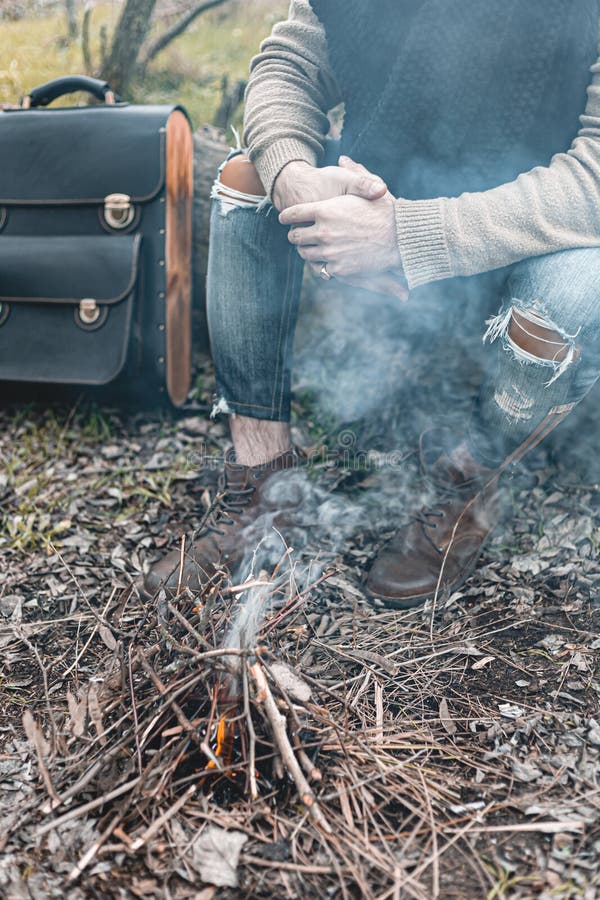 A Stock Photo of a Man in Nature Sitting by a Small Fire, Warming ...