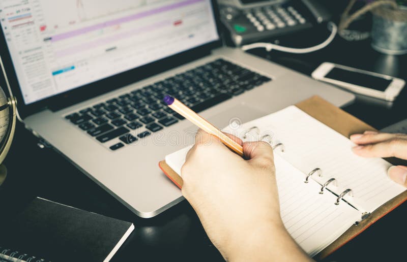 Hand Taking Note from Stock Trading Data on Computer Stock Photo ...