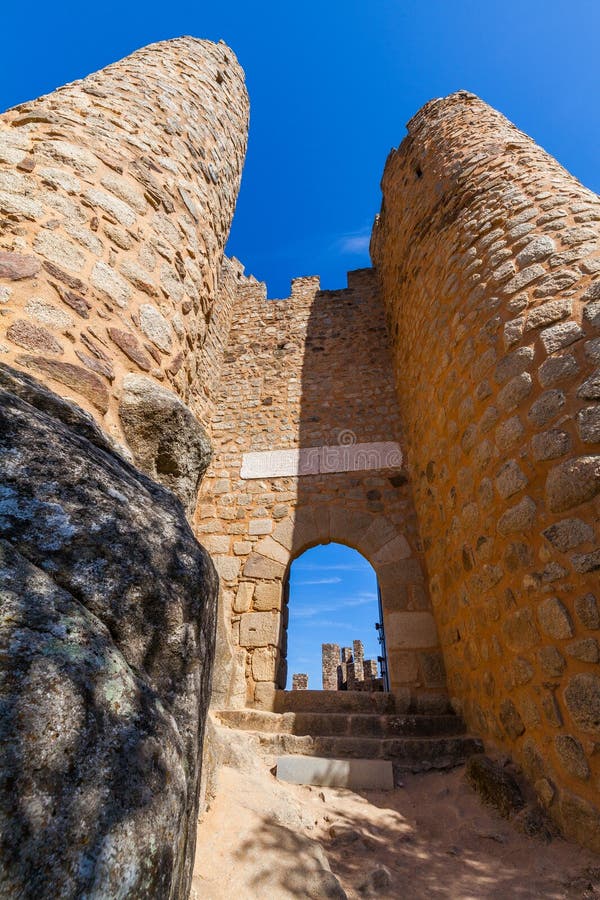 Stone Archway and Towering Castle Walls Set Against a Bright Blue Sky ...