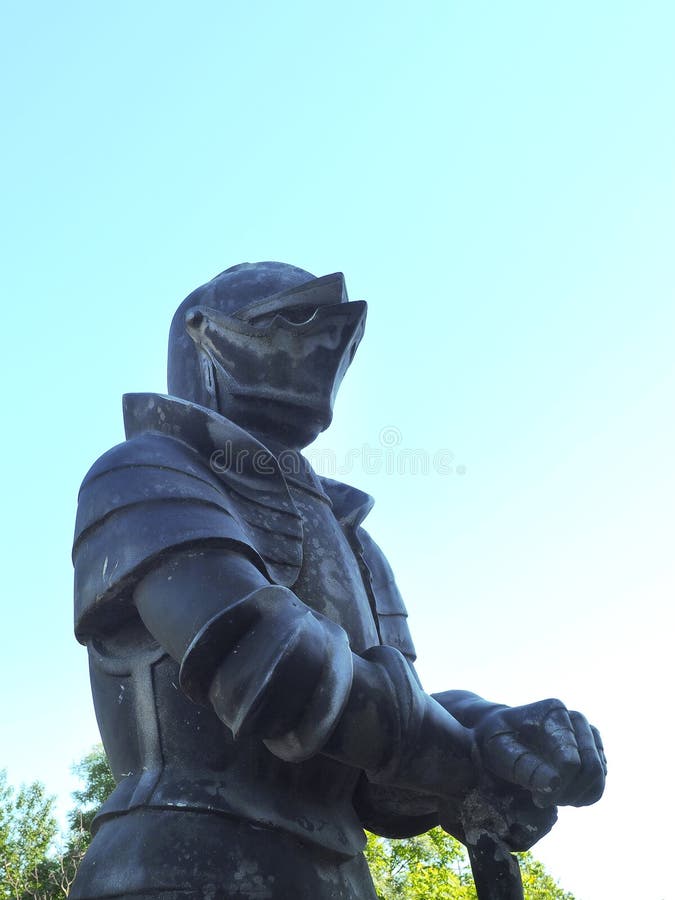 A Stone Monument of a Medieval Knight in Armor Stands Outdoors Against ...