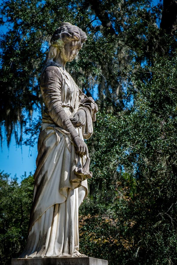 Stone Statue of a Woman Against a Background with Trees on a Sunny Day ...