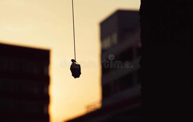 Stone on String Hanging in Front of Buildings at Sunset Stock Image ...
