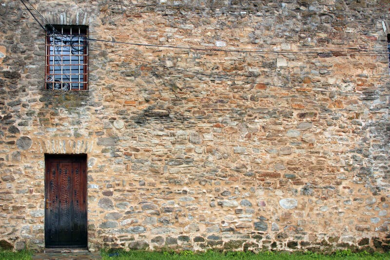 Stone Wall with Barred Window and Wooden Door Stock Photo - Image of ...