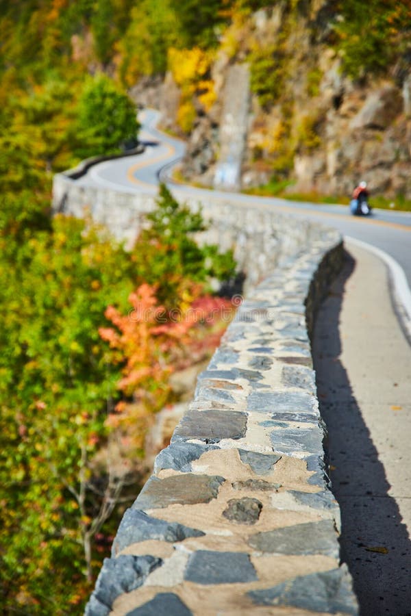 Stone Wall and Road Winding through Mountain Cliffs with Biker Going ...