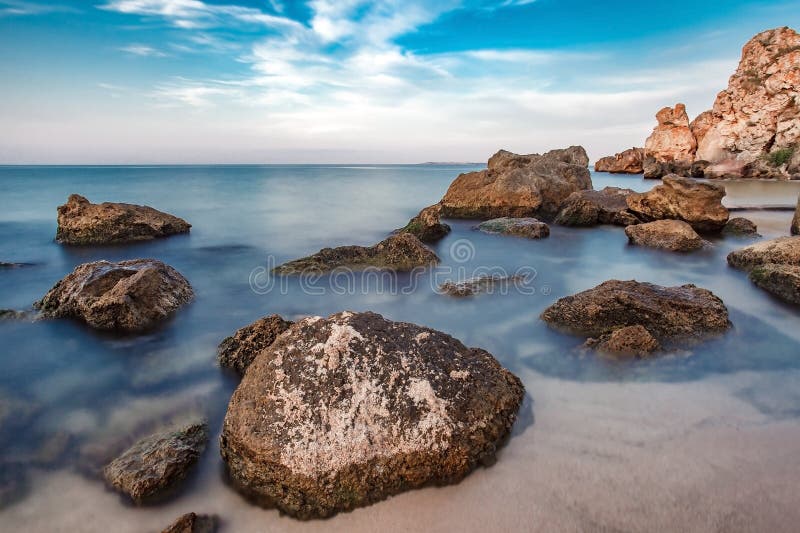 Stones in Water and Rocks on Seashore, Blurred Water Movement Stock ...