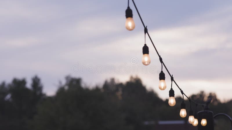 Strand of Edison Light Bulbs Glows Against Twilight Sky Stock Footage ...