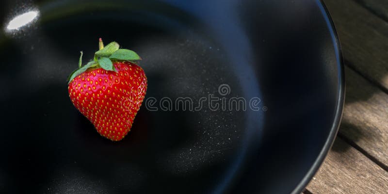A Strawberry in the Middle of a Black Plate Stock Photo - Image of ...