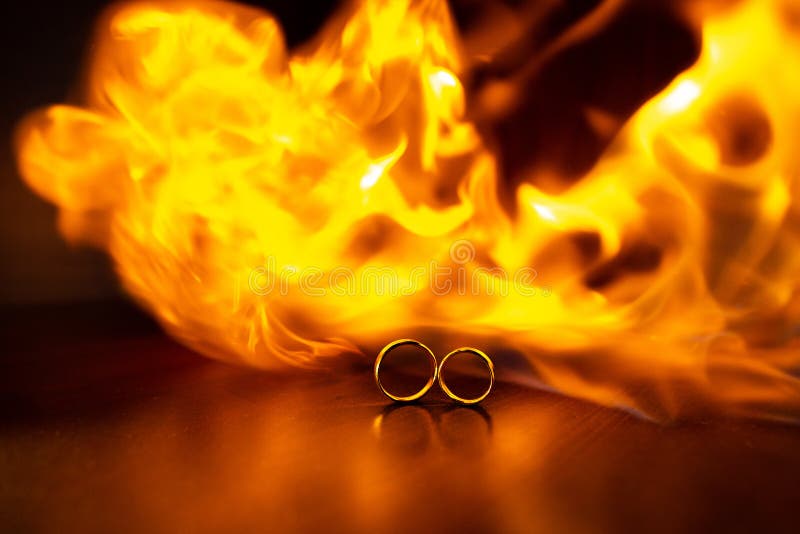 A Stream of Fire. Wedding Rings on Fire with Reflection on Black ...