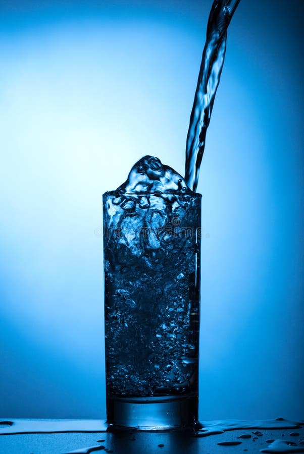 A Stream of Water Pours into the Glass Close-up. Water Spray, Blue ...