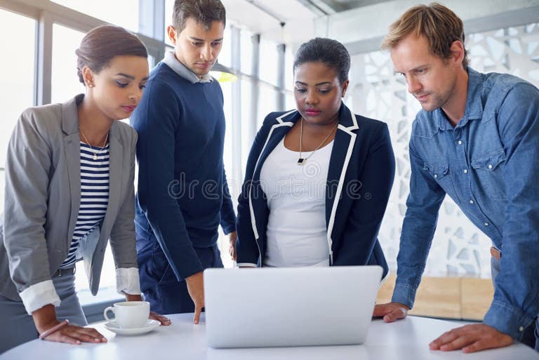 Streamlining Their Workflow. a Group of Coworkers Working Together on a Laptop in an Office ...