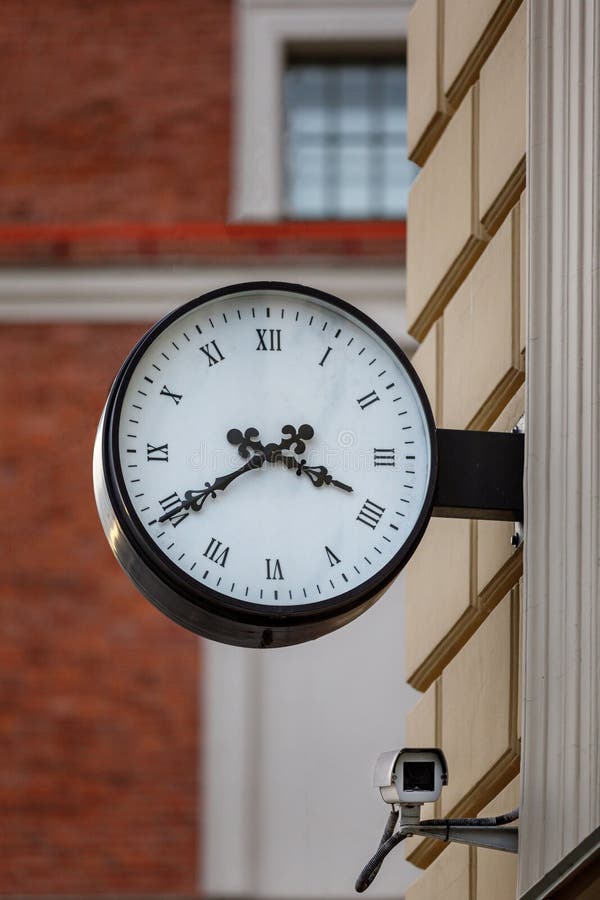 Street Clock and Security Camera on the Wall of the Building. Cctv and ...