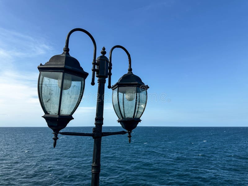 Street Lamp by the Ocean Under a Clear Blue Sky with Gentle Waves in ...