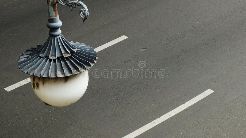 A Street Light with a White Shade is Hanging from a Pole on the Asphalt ...