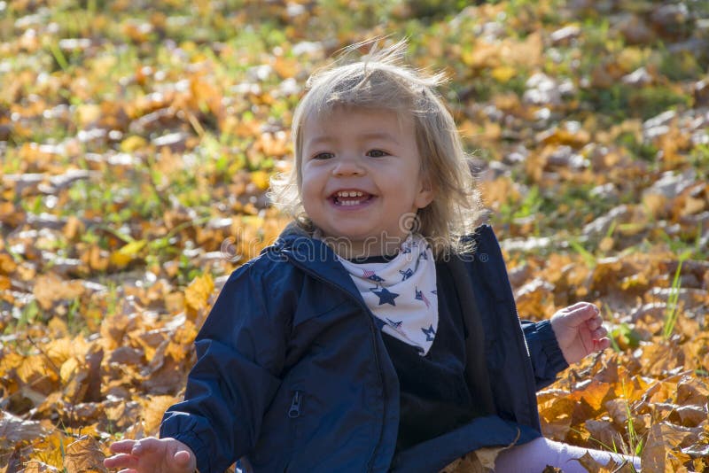 Street Portrait of a Happy Little Girl Sitting in a Pile of Yellow ... Street Portrait of a Happy Little Girl Sitting in a Pile of Yellow ...