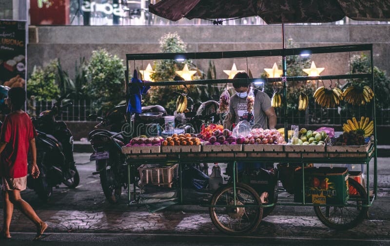 Street Vendor on an Empty Street with People Walking by at Night in the ...