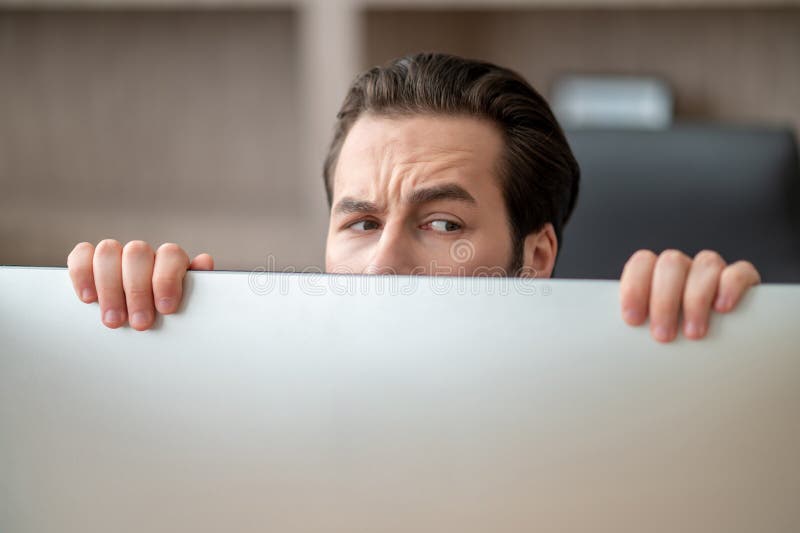 A Dark-haired Man Hiding Behind the Computer and Looking Stressed Stock ...