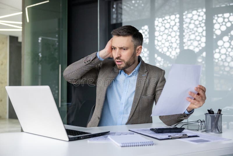 Stressed Businessman Reviewing Documents in Modern Office while Working ...