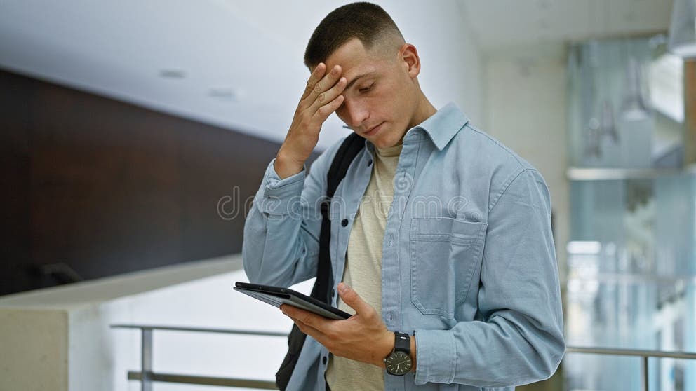 A Stressed Hispanic Man with a Headache Holding a Tablet Inside a ...