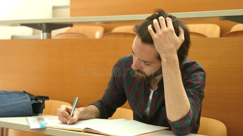 Stressed Student Studying and Taking Notes in the Library Surrounded by ...