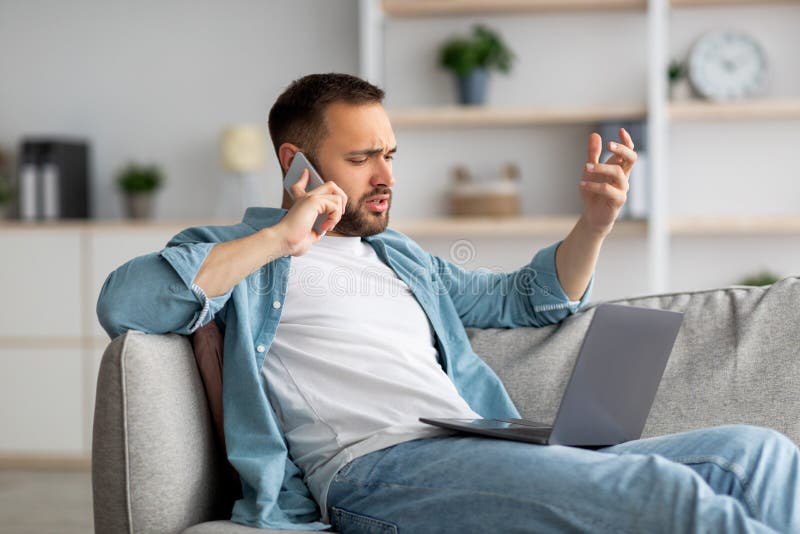 Stressed Young Businessman Using Laptop and Making Call on Mobile Phone ...