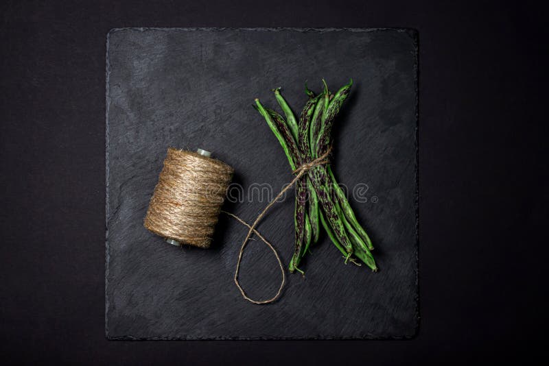 Green String Beans Tied in a Bunch Hanging on a Black Background Stock ...
