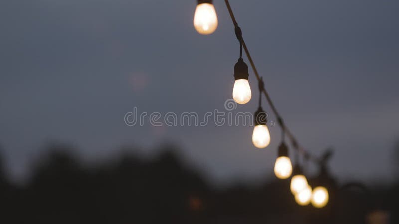 String of Edison Light Bulbs Glows Against Dusk Sky Stock Video - Video ...