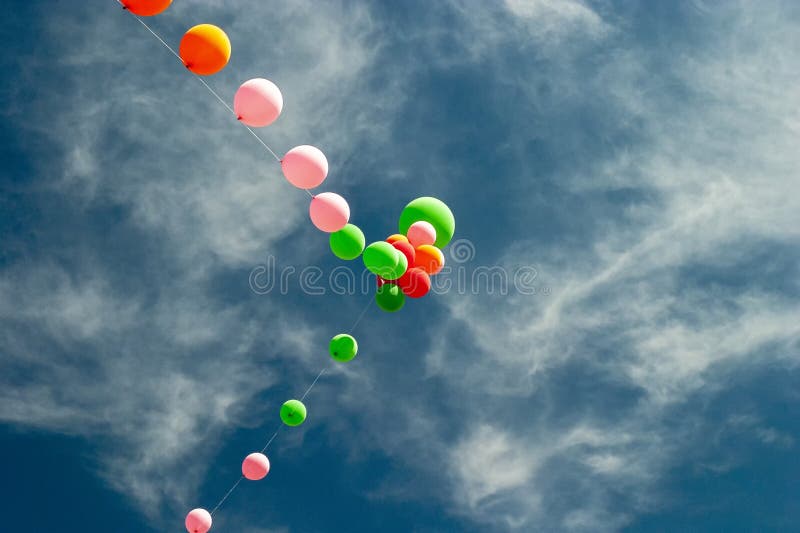A String of Large and Small Colorful Balloons Against a Blue Sky Stock ...