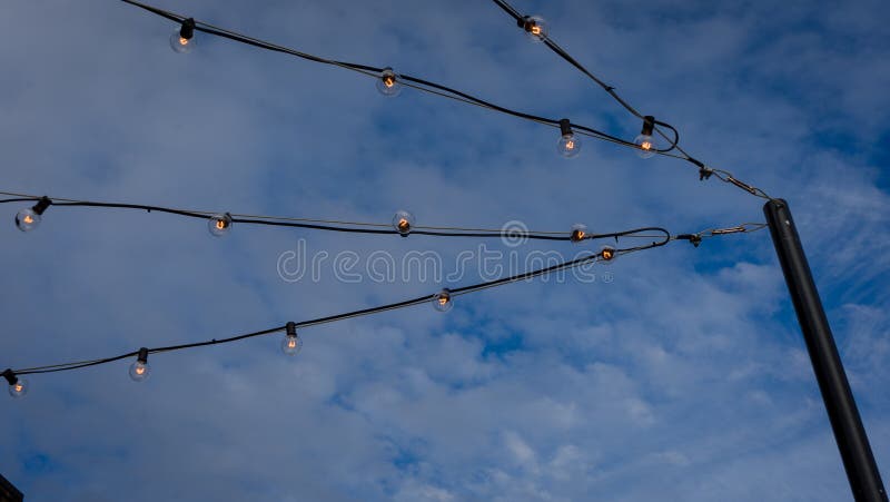 String of Lights Under the Bright Blue Cloudy Sky. Stock Image - Image ...