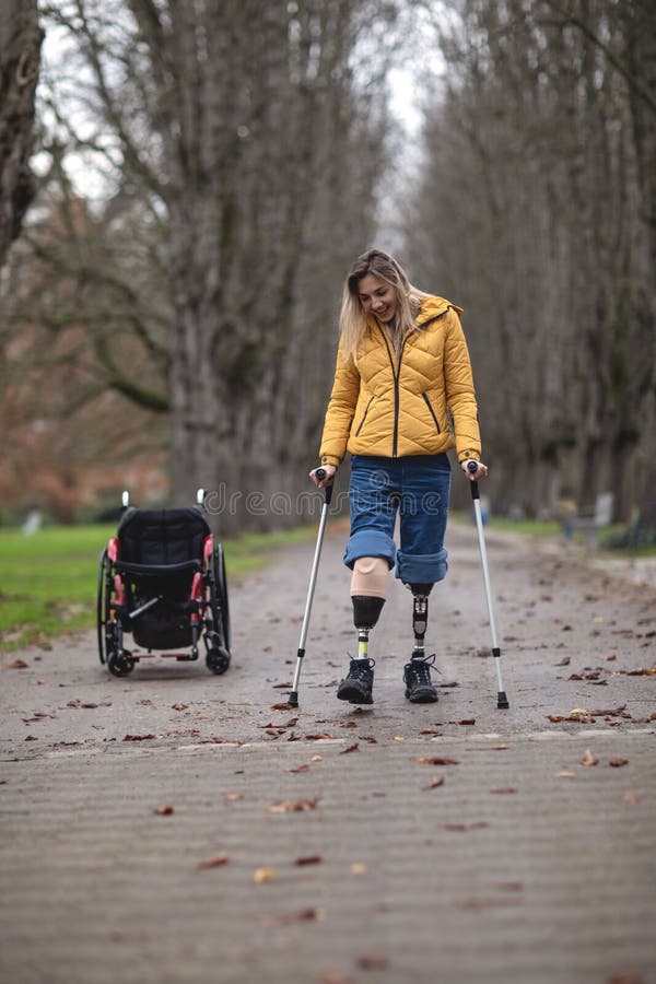 A Disabled Girl without Legs is Standing on Dentures Near a Wheelchair ...