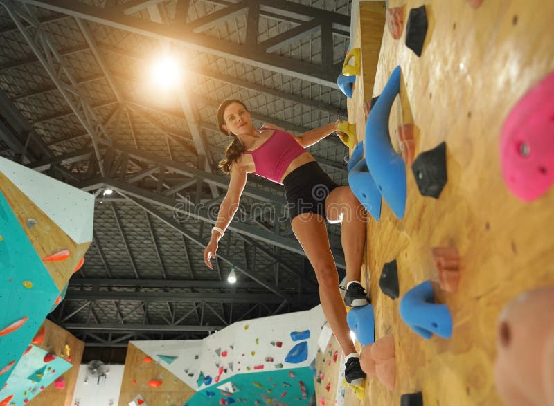 A Strong Female Climber Climbs an Artificial Wall with Colorful Grips ...