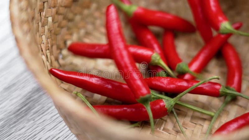 Strong Intensity Red Chili Peppers Falling into a Rustic Braided Bowl ...