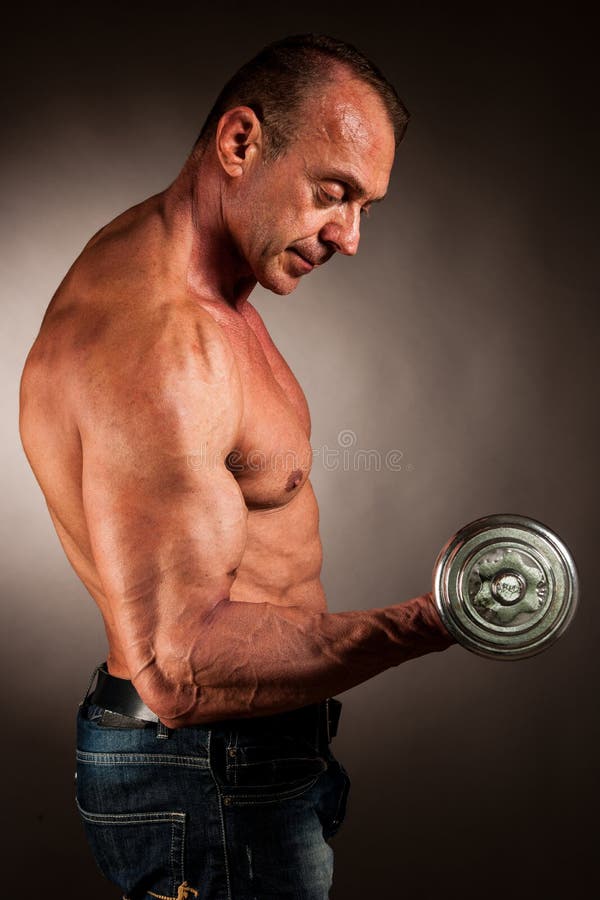 Strong Male Athlete Works Out with Dumbbells in Studio Over Dark Stock ...