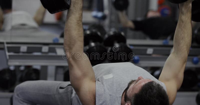 A Man Press Dumbbells Lying on Bench at the Gym Stock Video - Video of ...