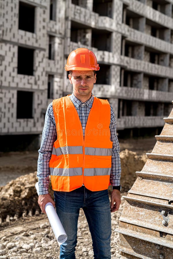 A Strong Man Working in Uniform and Helmet Stands Under an Unfinished ...
