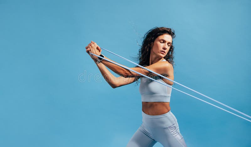 Strong Woman Exercising with Resistance Band on Blue Background Stock ...