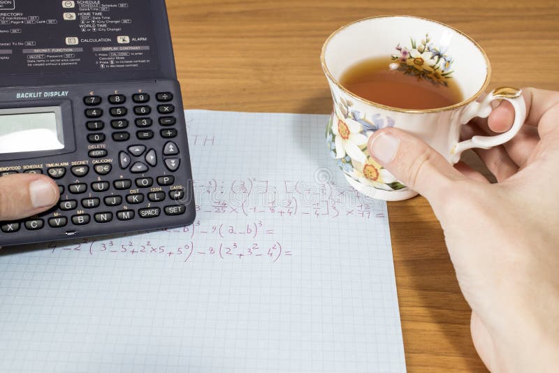 A Student is Doing Math Homework with a Calculator and an Hot Cu Stock ...