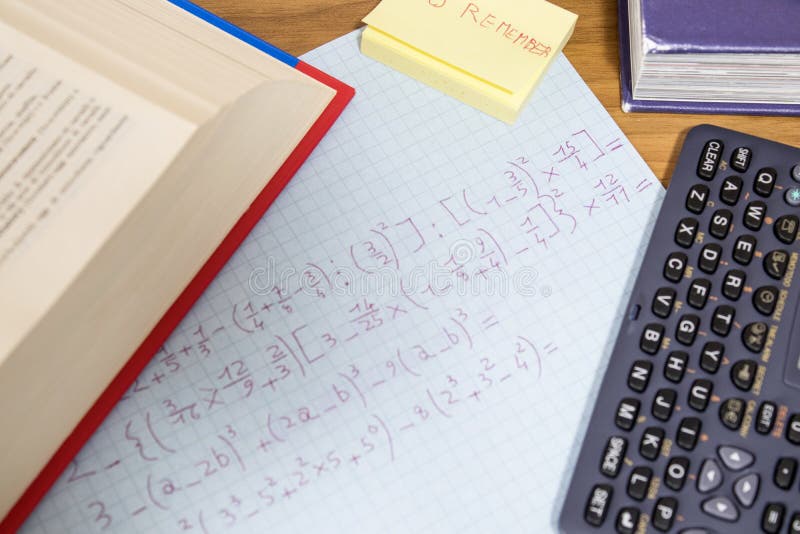 A Student is Doing Math Homework with a Pen, a Calculator and an Stock ...