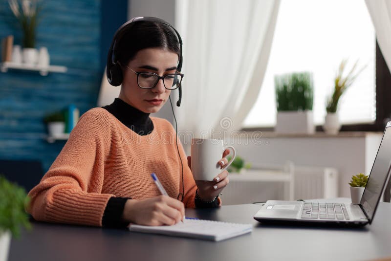 Student with Headphones Listening To Online Course and Taking Notes ...