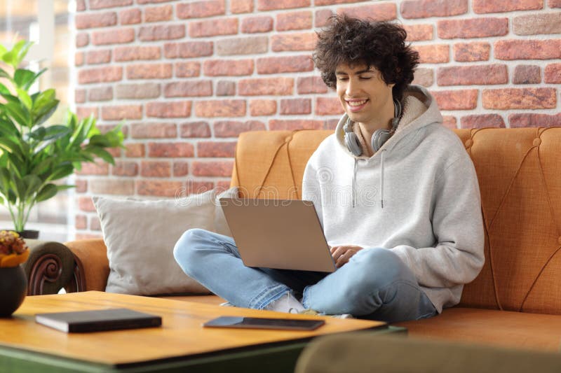 Student with Headphones Sitting in a Cafe and Using a Laptop Stock ...
