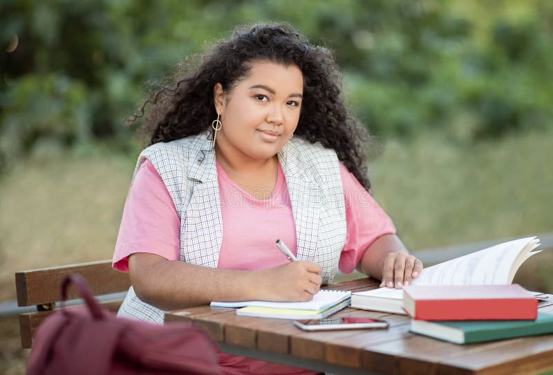 Student Lady Taking Notes from Textbook Smiling at Camera Outdoors ...